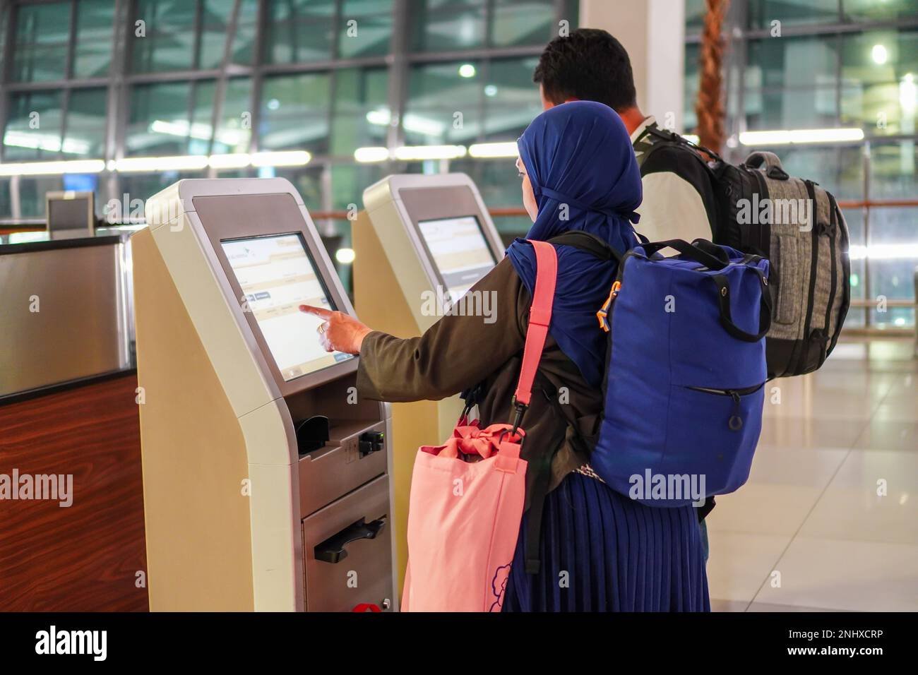 A couple checking-in flights using a smartphone at a self-check-in ...