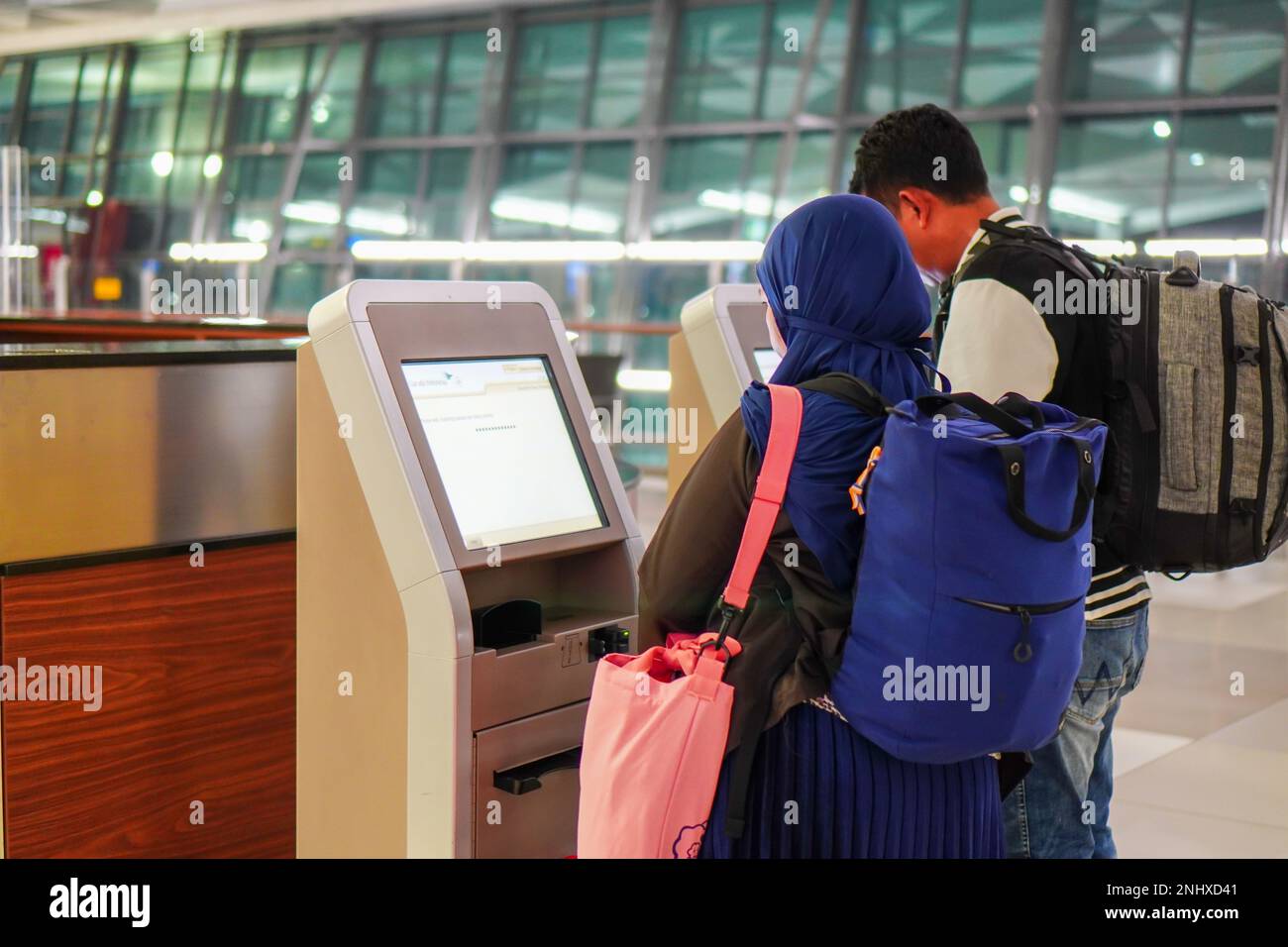 A couple checking-in flights using a smartphone at a self-check-in ...