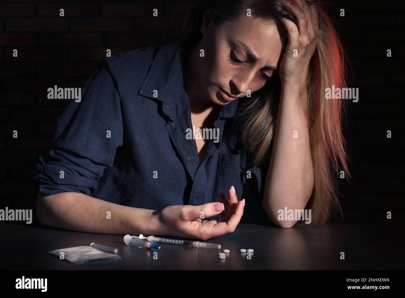 Addicted woman at table with different drugs on black background Stock ...