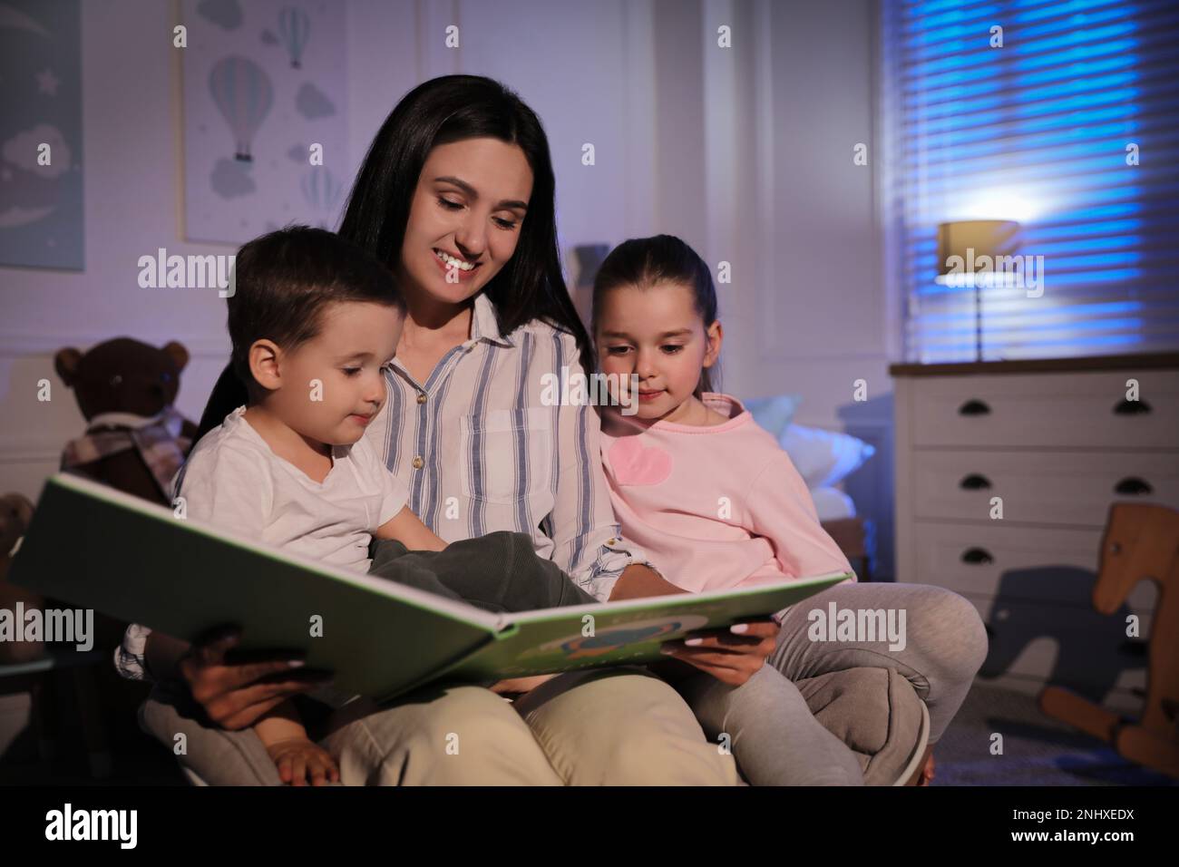 Mother reading bedtime story to her children at home Stock Photo - Alamy