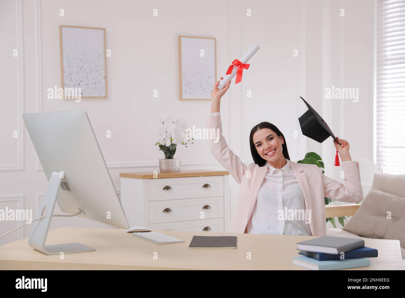 Happy student with graduation hat and diploma at workplace in office ...