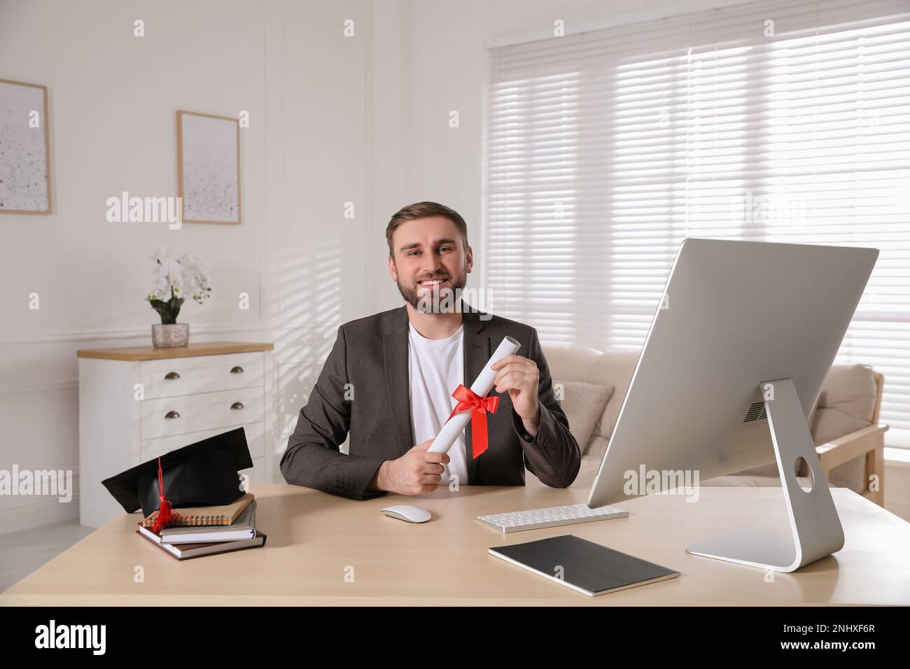 Happy student with graduation hat and diploma at workplace in office ...