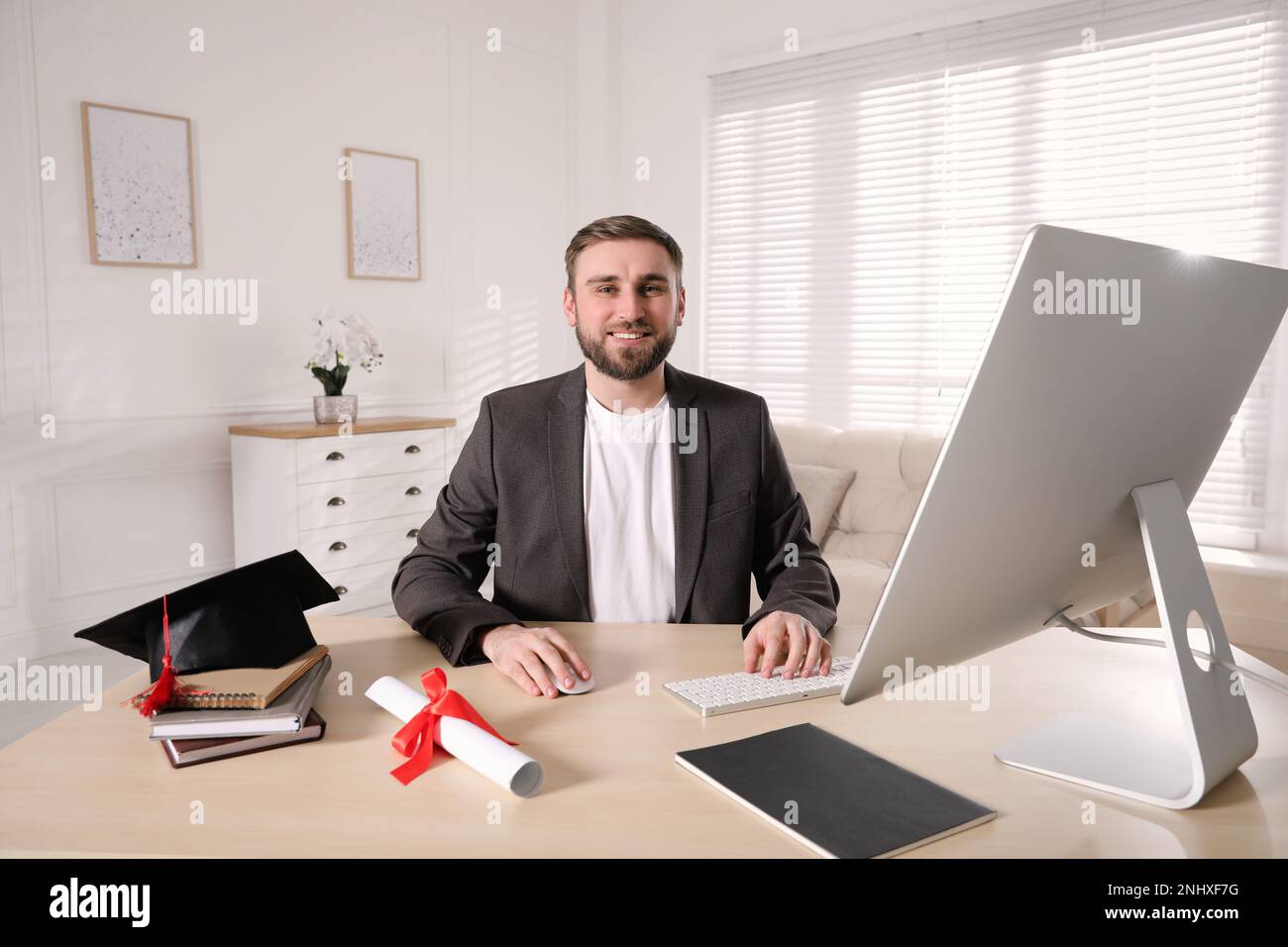 Happy student with graduation hat and diploma at workplace in office ...