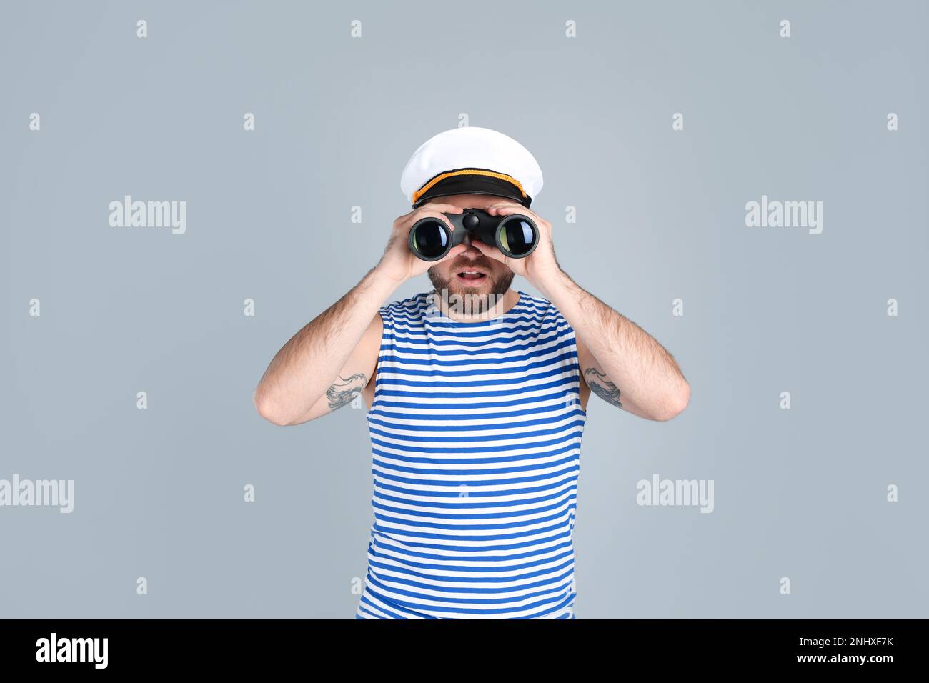 Sailor with binoculars on light grey background Stock Photo - Alamy