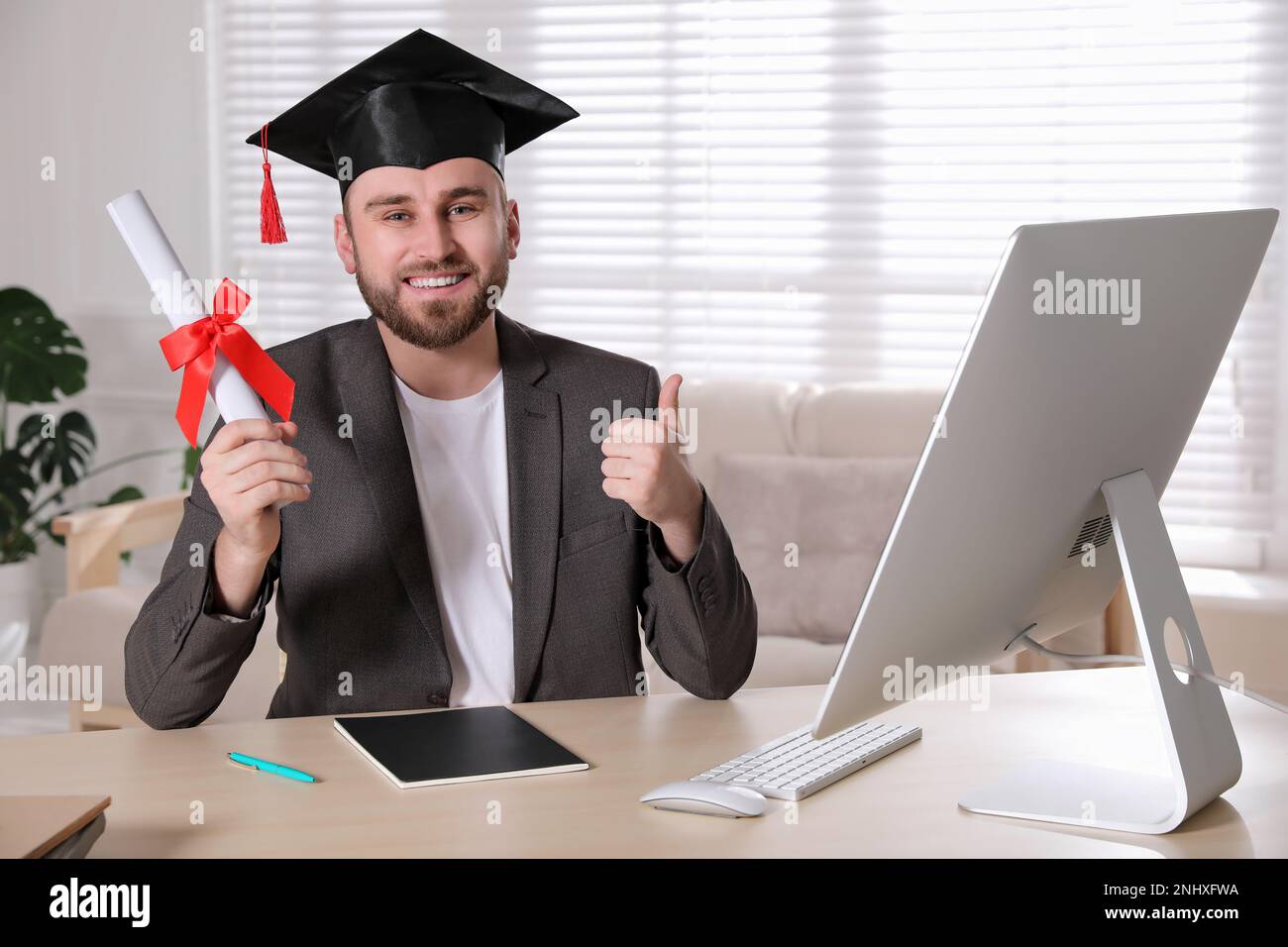 Happy student with graduation hat and diploma at workplace in office ...
