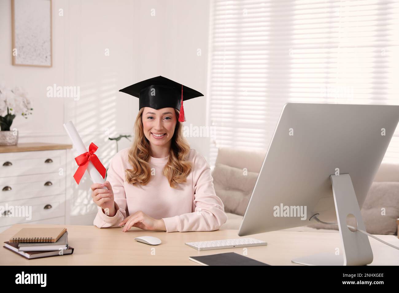 Happy student with graduation hat and diploma at workplace in office ...