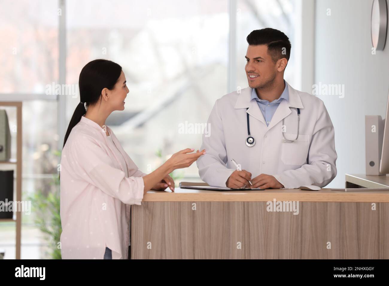 Doctor working with patient at reception in hospital Stock Photo - Alamy
