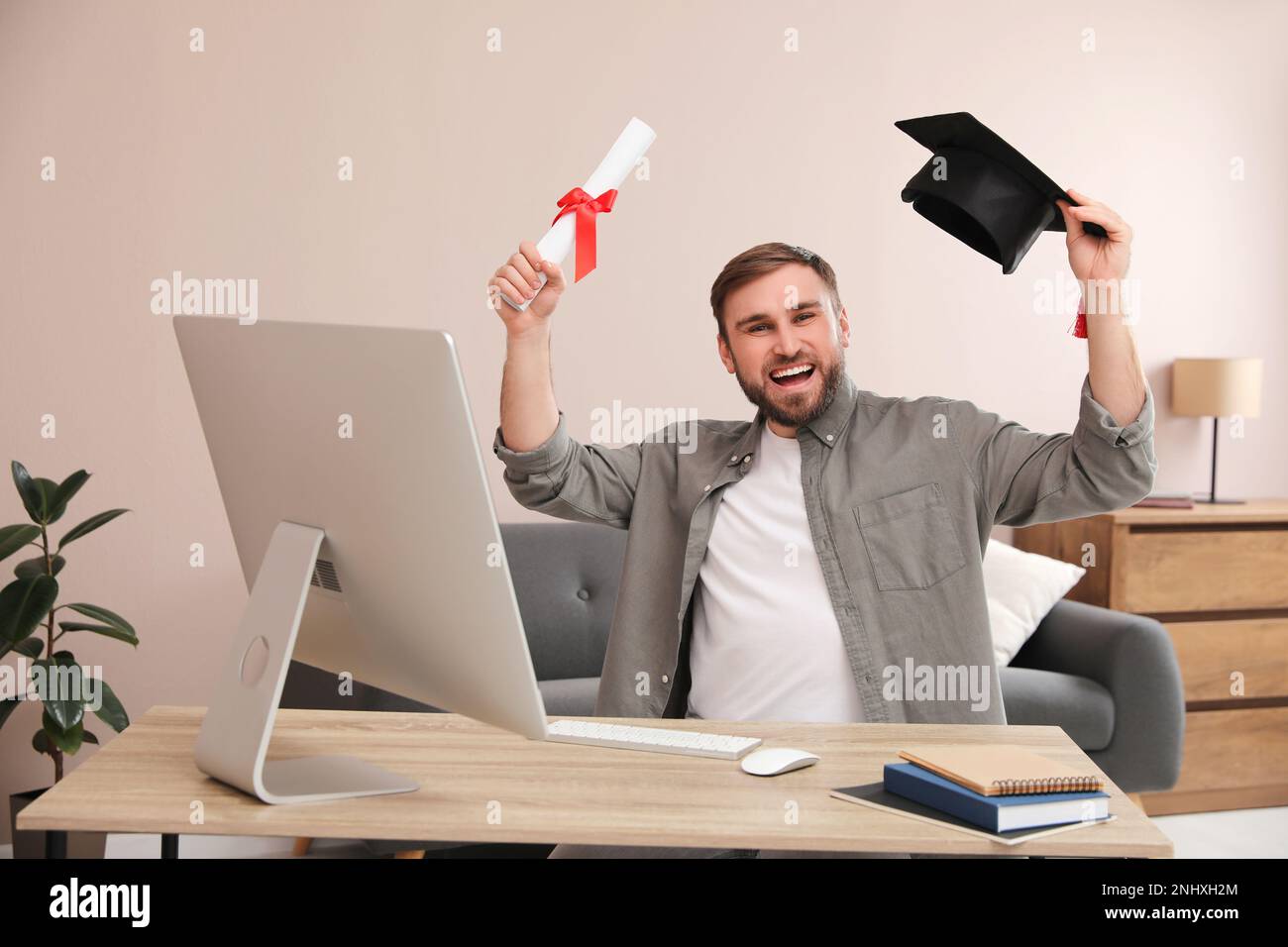 Emotional student with graduation hat and diploma at workplace in ...