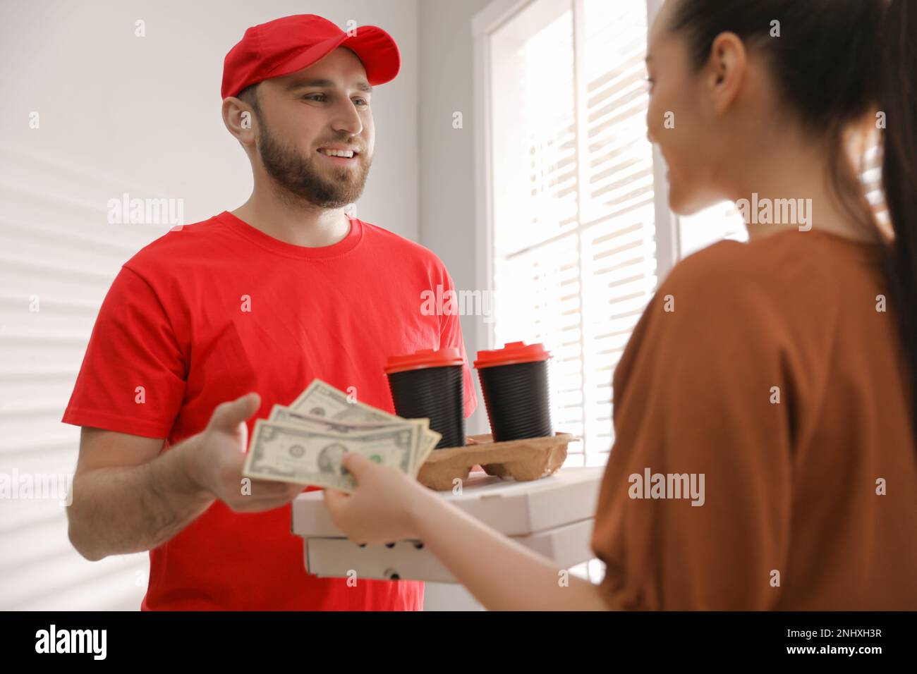 Young deliveryman receiving tips from woman indoors Stock Photo - Alamy
