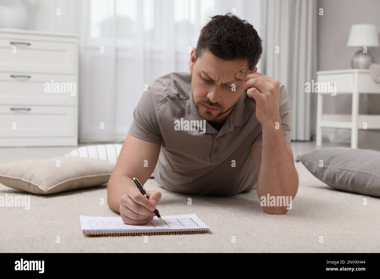 Man solving sudoku puzzle on floor at home Stock Photo - Alamy