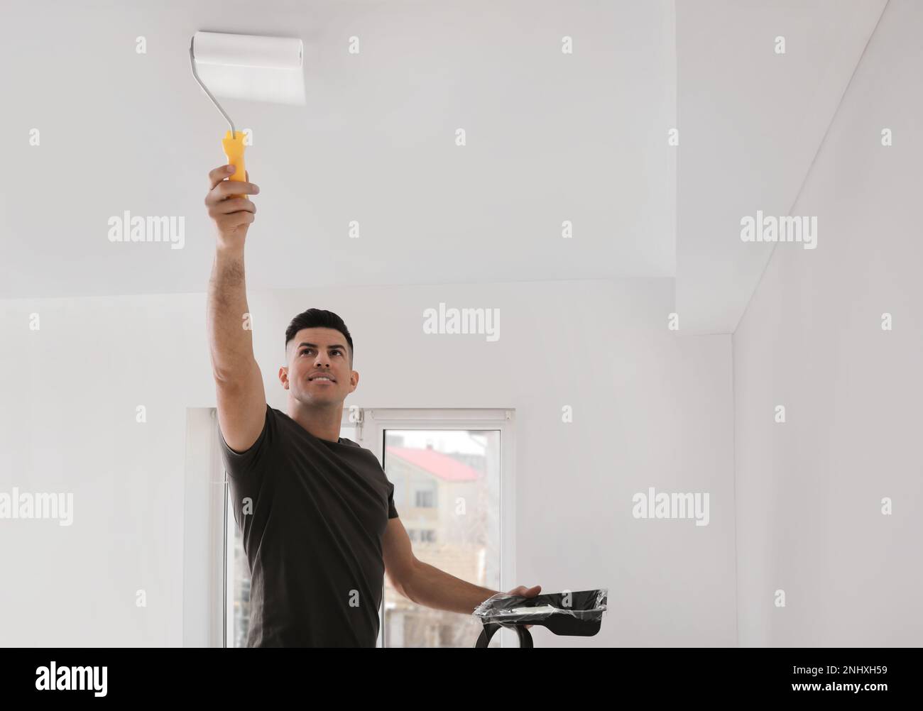 Man painting ceiling with roller in room. Space for text Stock Photo ...