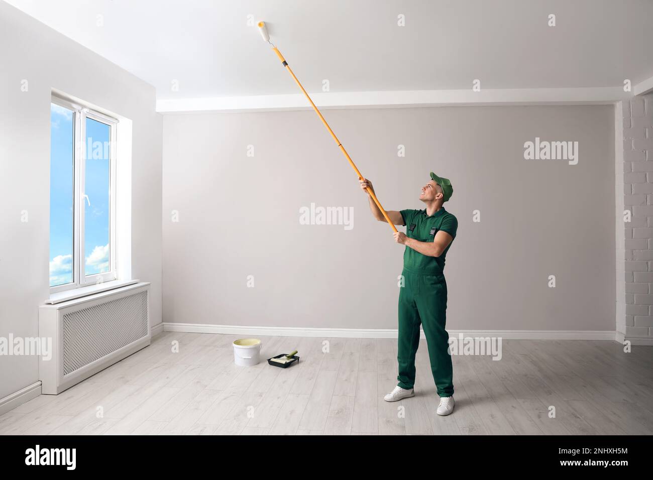 Man painting ceiling with roller in room Stock Photo - Alamy
