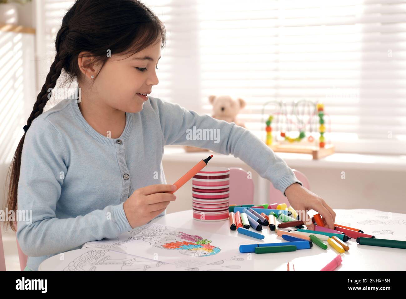 Cute child coloring drawing at table in room Stock Photo - Alamy