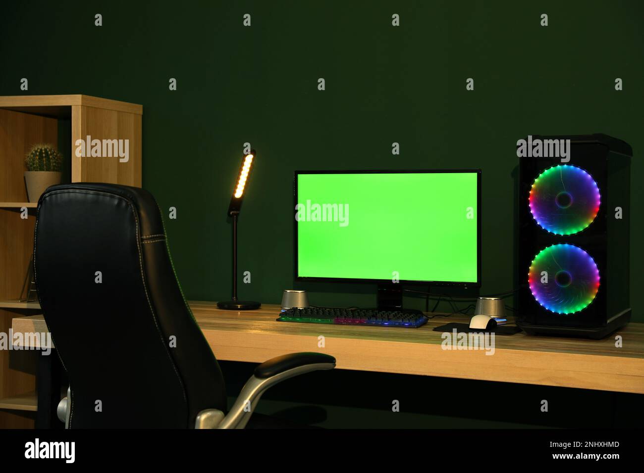 Modern computer and RGB keyboard on wooden table indoors. Mockup green ...