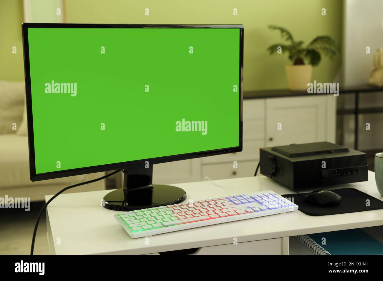 Modern computer and RGB keyboard on white table indoors. Mockup green ...
