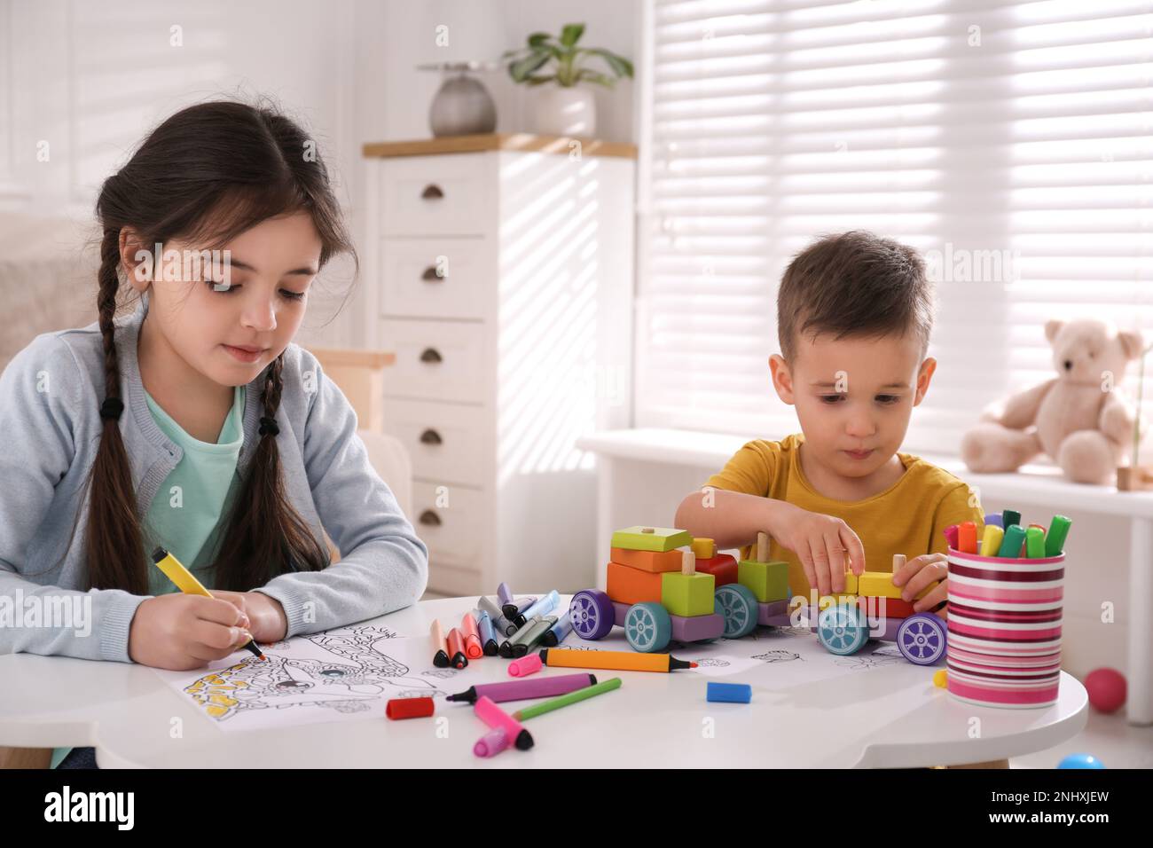 Cute children coloring drawing and playing at table in room Stock Photo ...