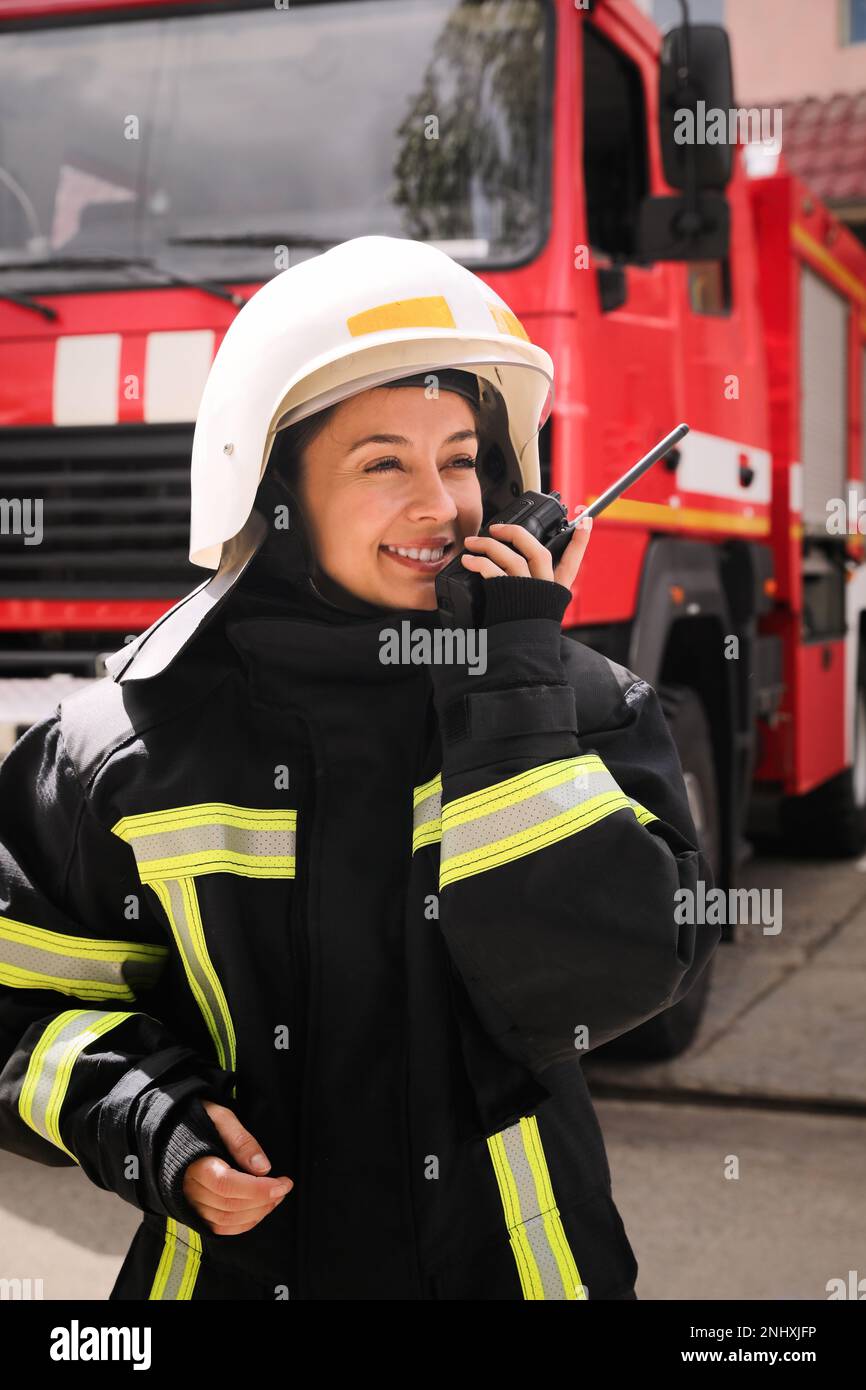 Firefighter in uniform using portable radio set near fire truck ...