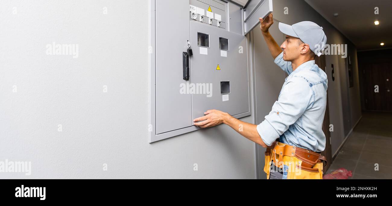 An electrician working on an industrial breaker panel. Model is an actual electrician performing ...