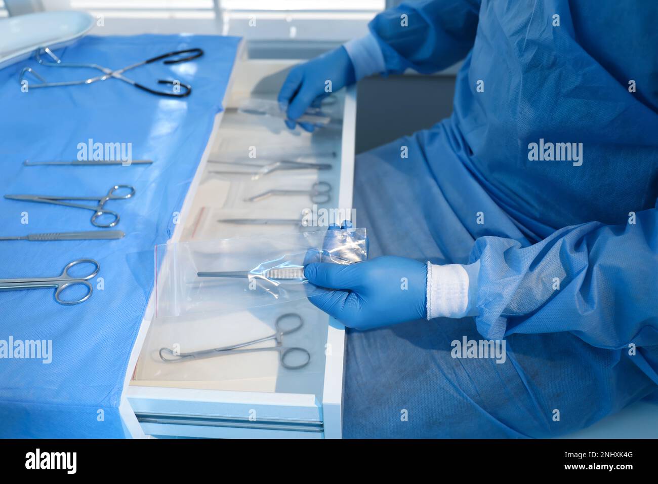 Doctor putting medical forceps into drawer indoors, closeup. Table with ...