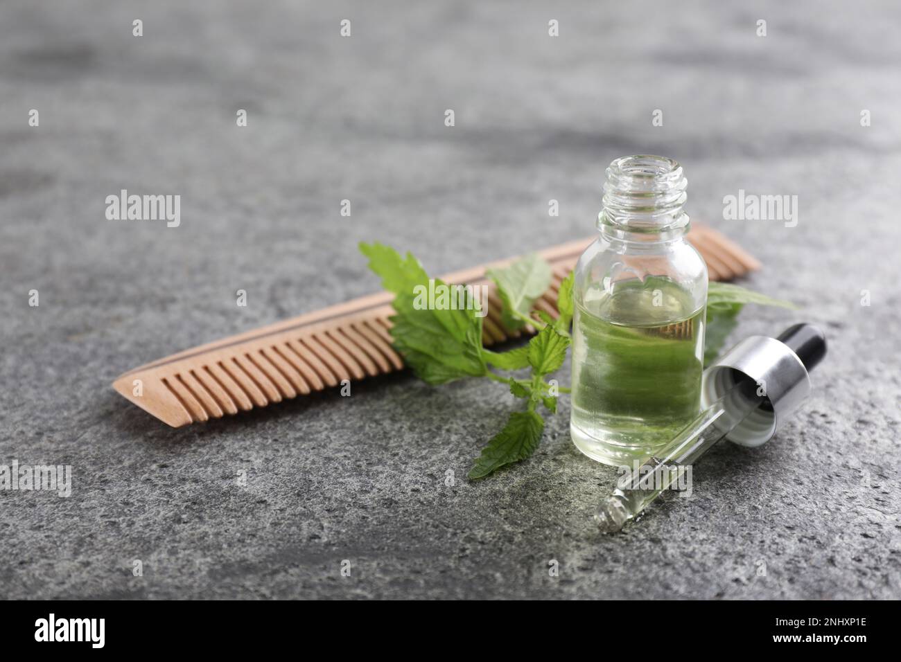 Stinging nettle, extract and comb on grey background. Natural hair care ...