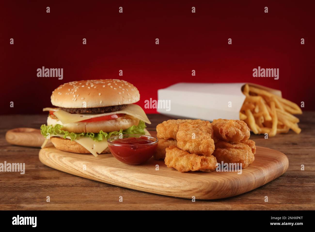 Delicious fast food menu on wooden table against red background Stock ...
