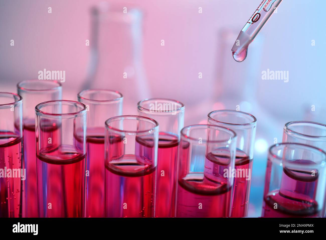 Dripping reagent into test tube with red liquid, closeup. Laboratory ...