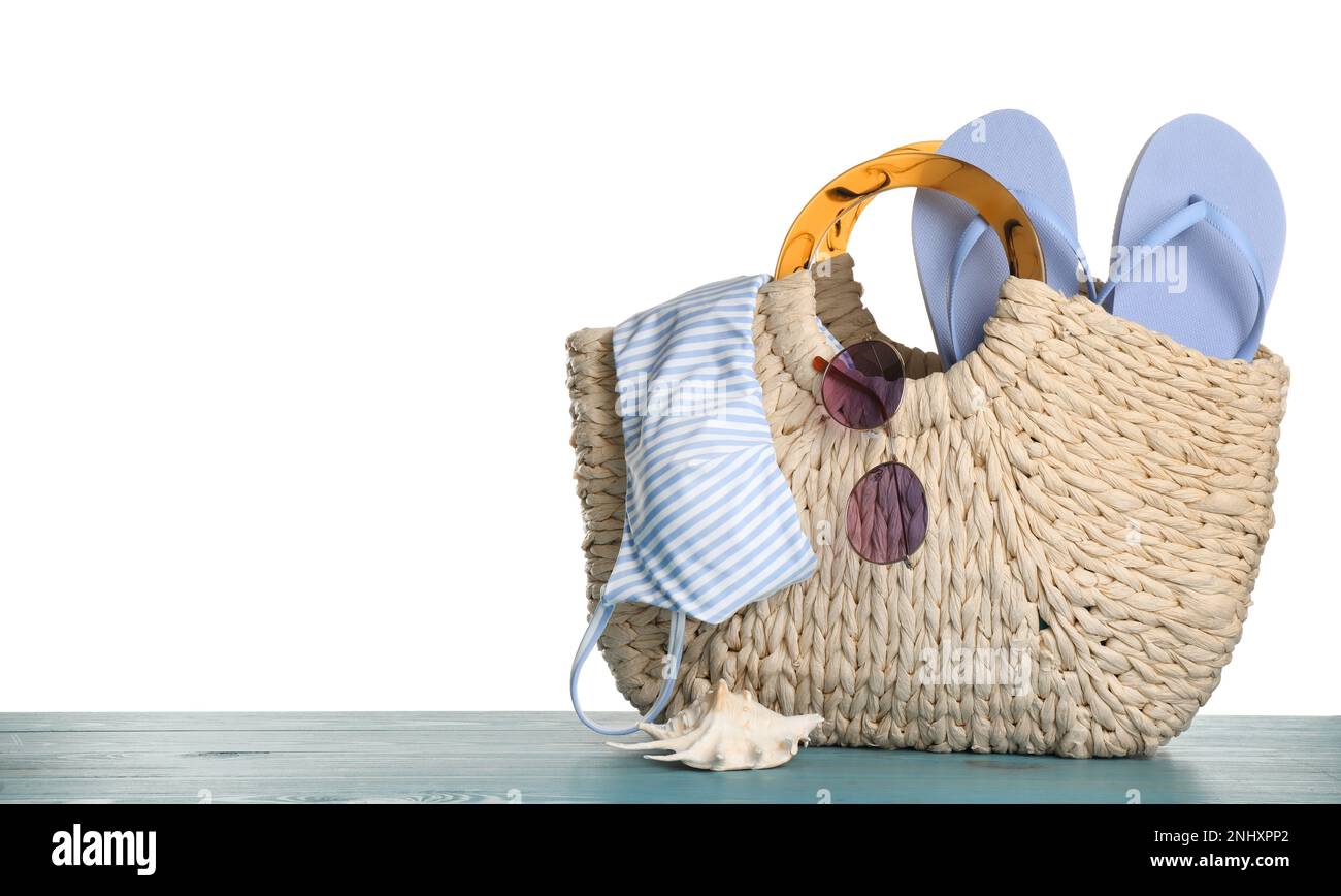 Bag with different beach objects on turquoise wooden table against ...