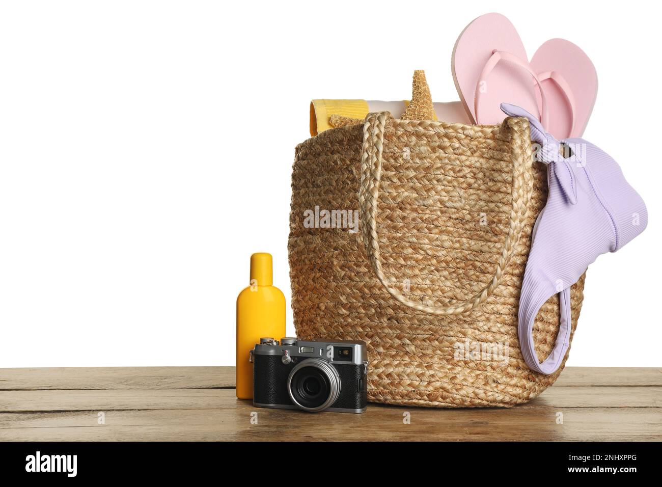 Bag with different beach objects on wooden table against white ...