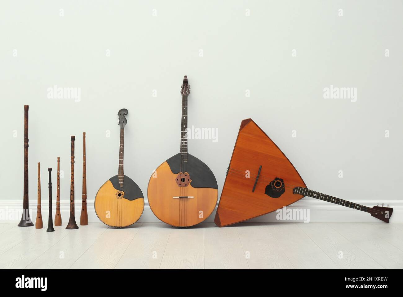 Set of different wooden musical instruments near white wall indoors ...