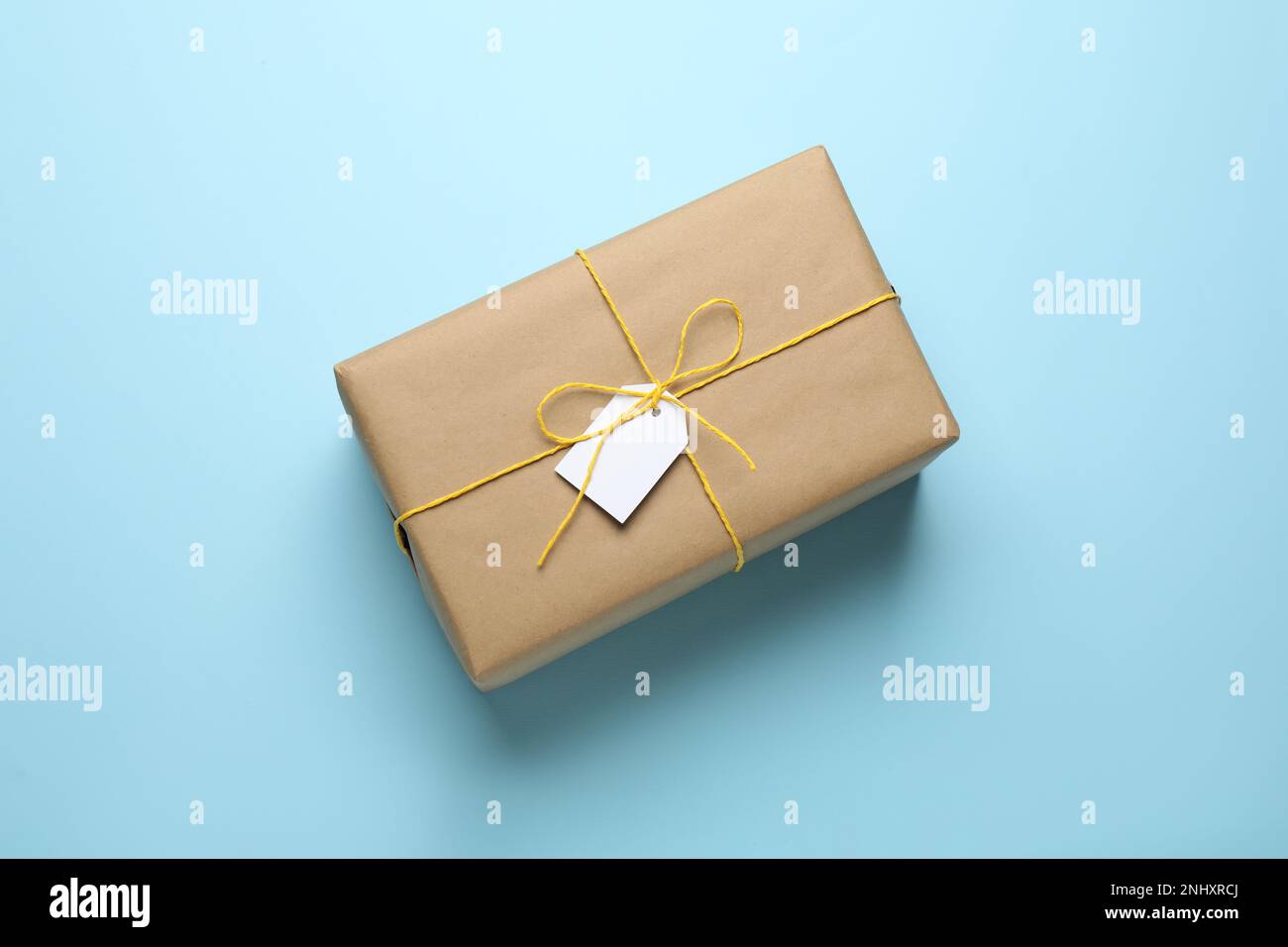 Parcel wrapped in kraft paper with tag on light blue background, top ...