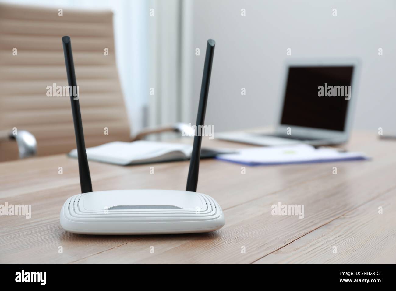 Modern Wi-Fi router on wooden table with laptop indoors Stock Photo - Alamy