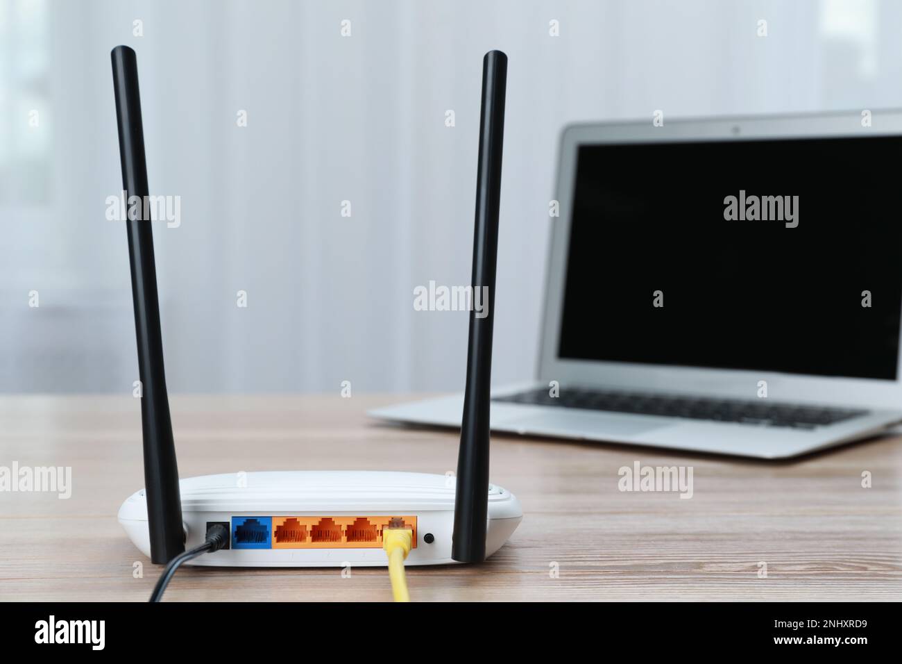 Modern Wi-Fi router and laptop on wooden table indoors Stock Photo - Alamy