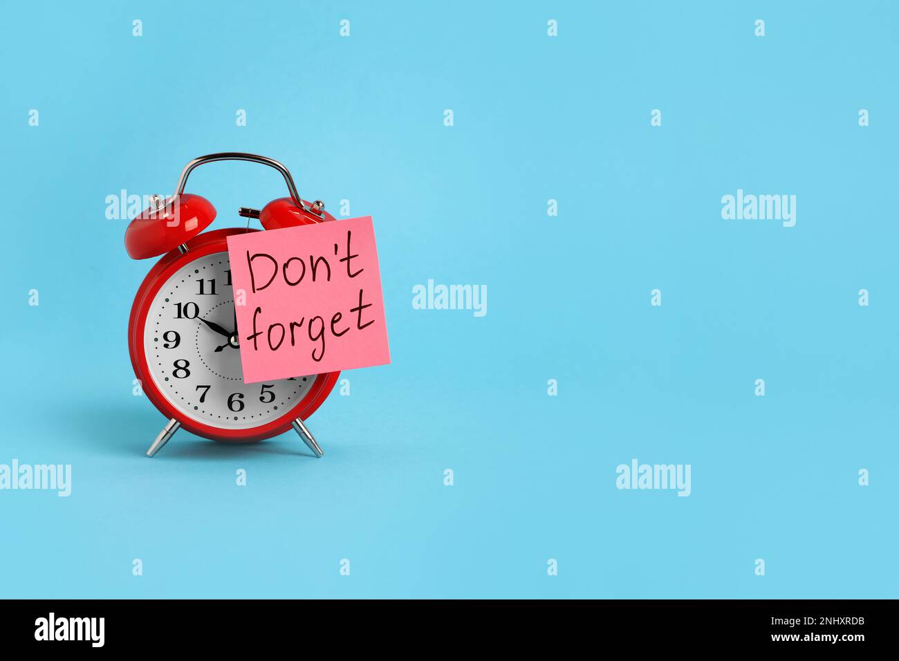 Alarm clock and reminder note with phrase Don't forget on light blue ...
