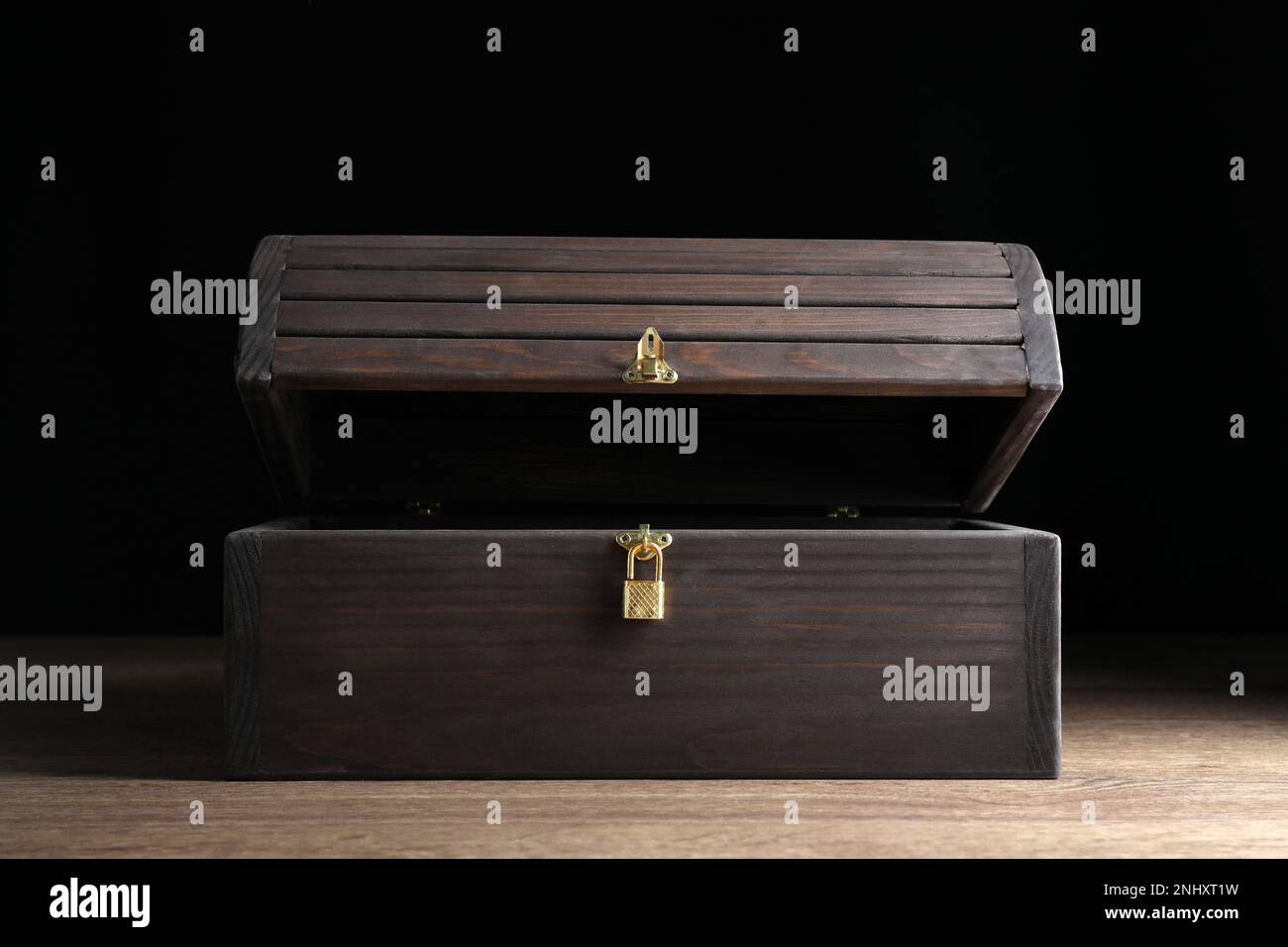 Open treasure chest on wooden table against black background Stock ...