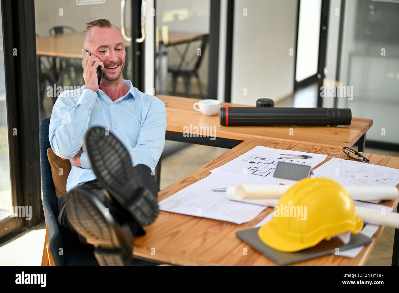 Happy and chilling Caucasian male engineer is on the phone with someone ...