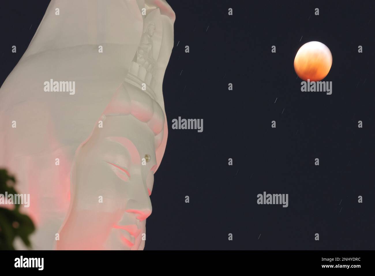 A total lunar eclipse is seen with Statue of Mercy Kannon in Kurume ...