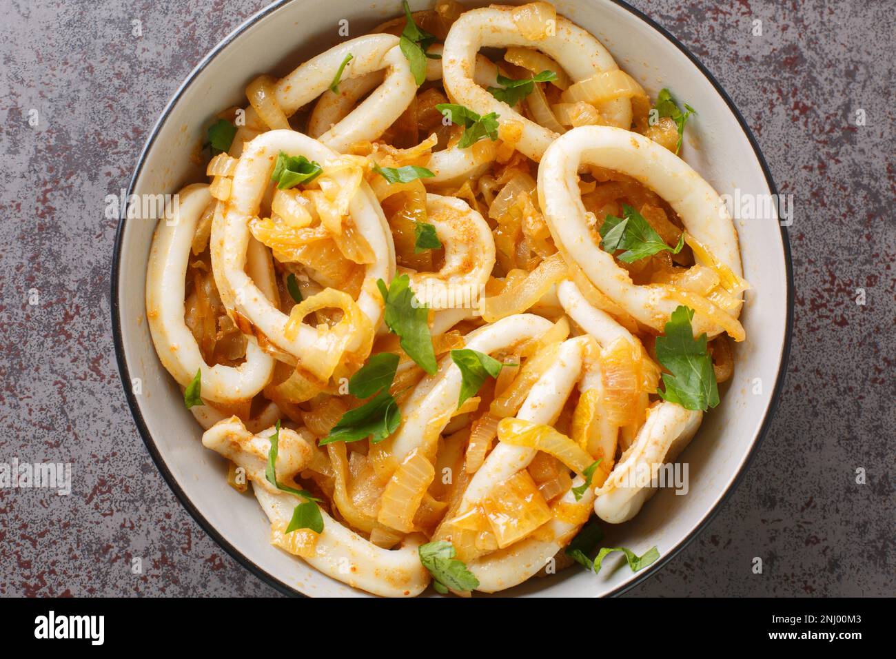 Squid rings with onions cooked in white wine close-up in a bowl on the ...