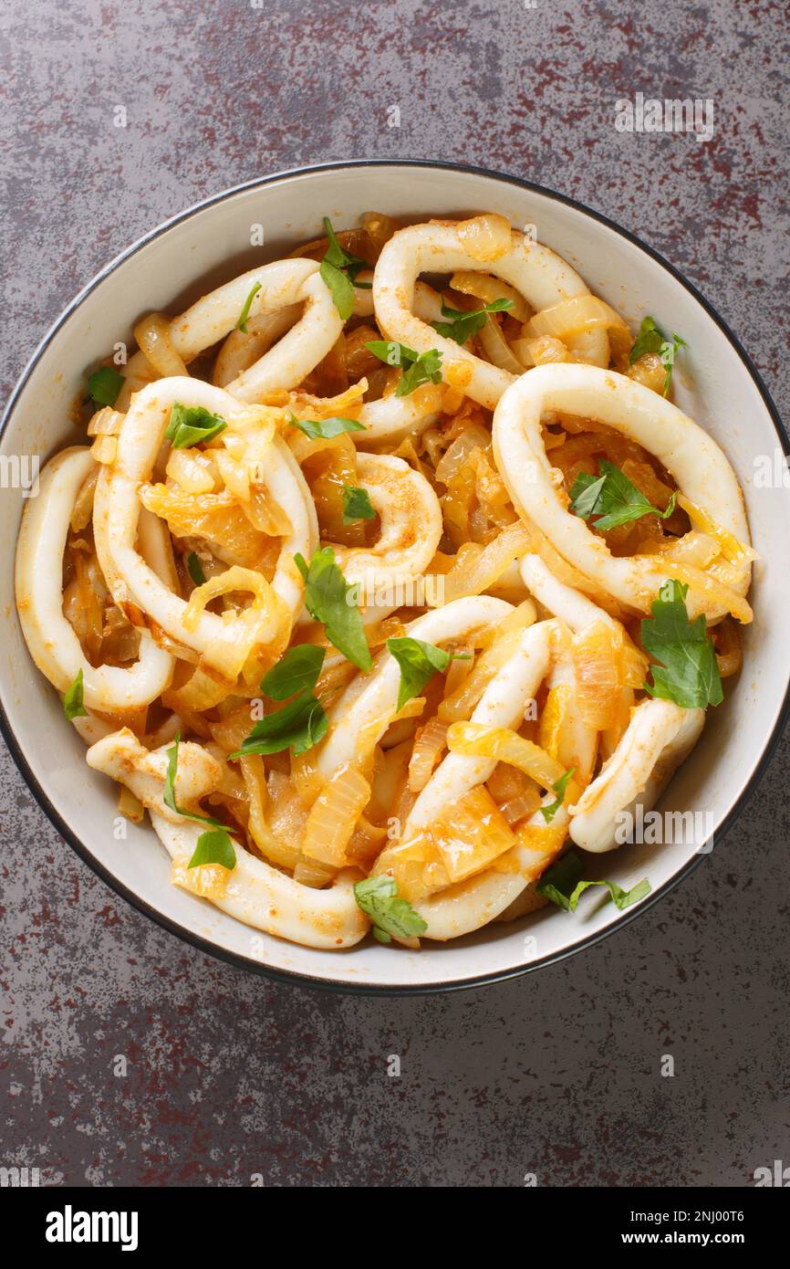 Spanish cuisine stewed calamari with onions in white wine close-up in a ...