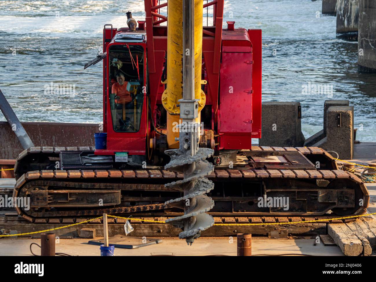 A crane operator uses a crane-mounted drill to burrow holes into the ...