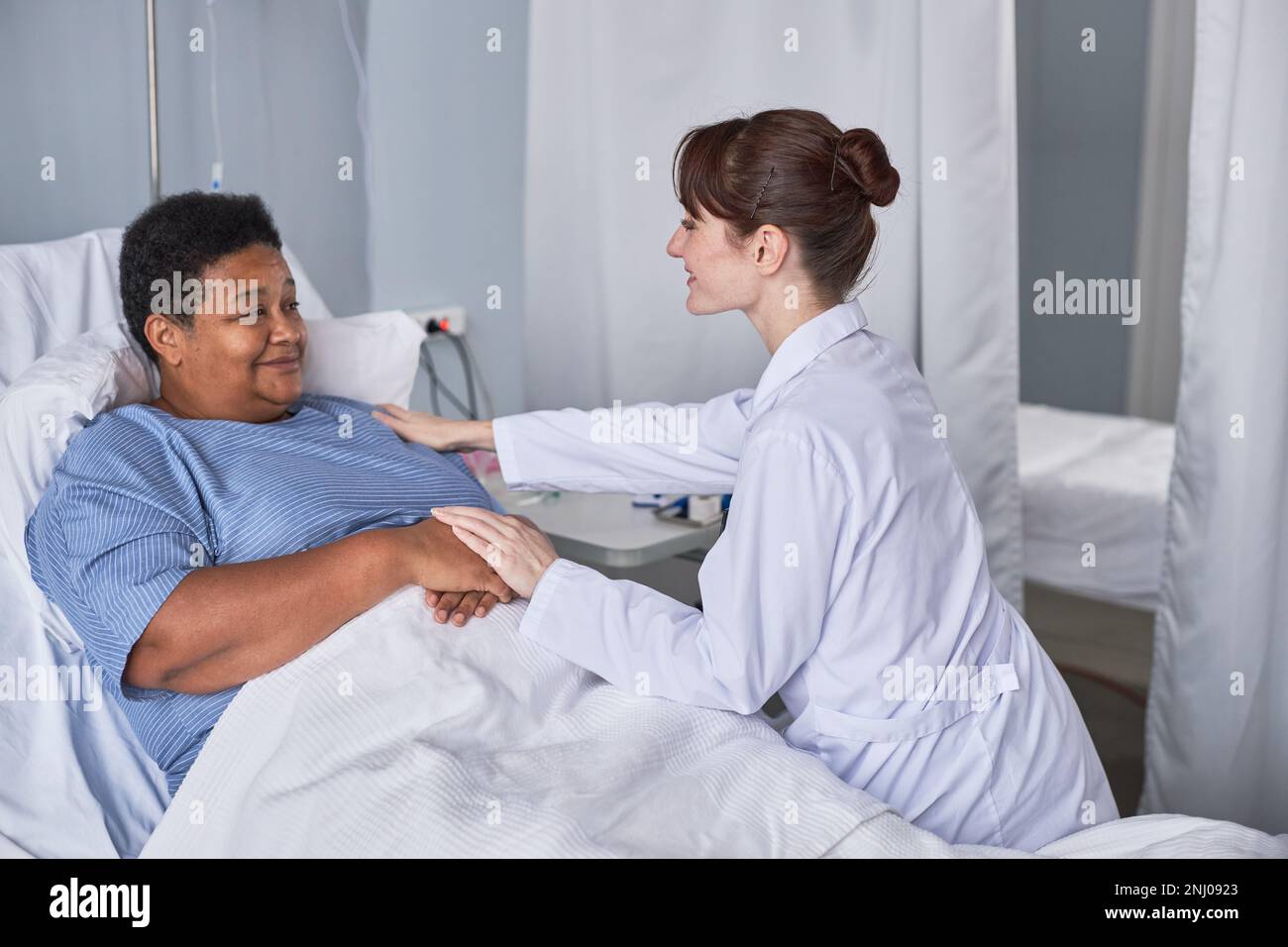Side view portrait caring young nurse supporting senior female patient ...