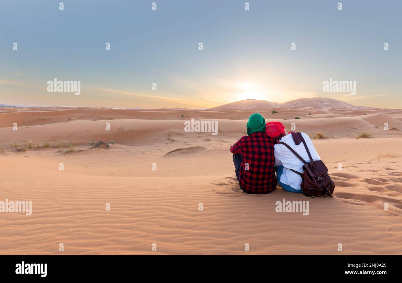Desert Sunset. Romantic couple sitting enjoying the warm colors of ...