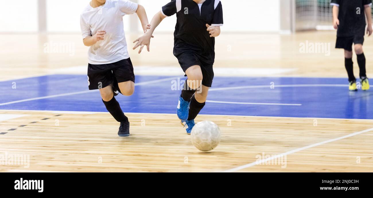 School boys on indoor football tournament game. Football futsal players ...