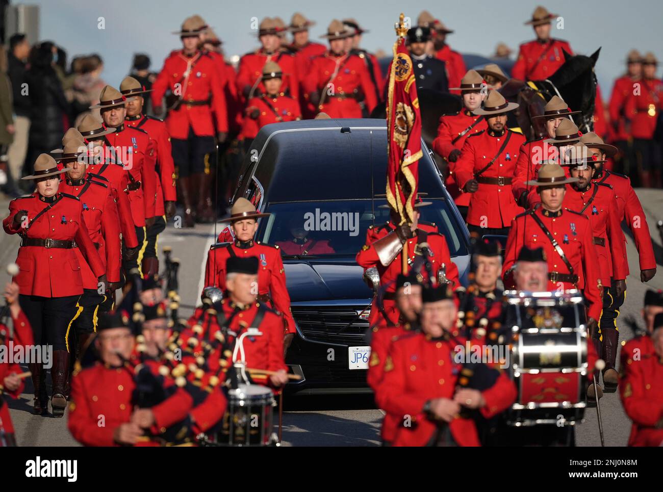 Royal Canadian Mounted Police officers march alongside a hearse ...