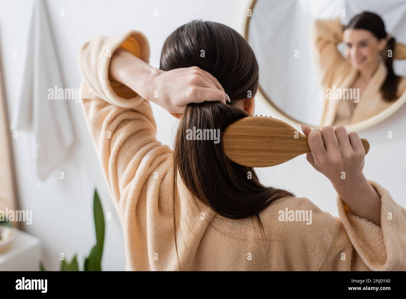 back view of young brunette woman brushing hair in bathroom,stock image ...