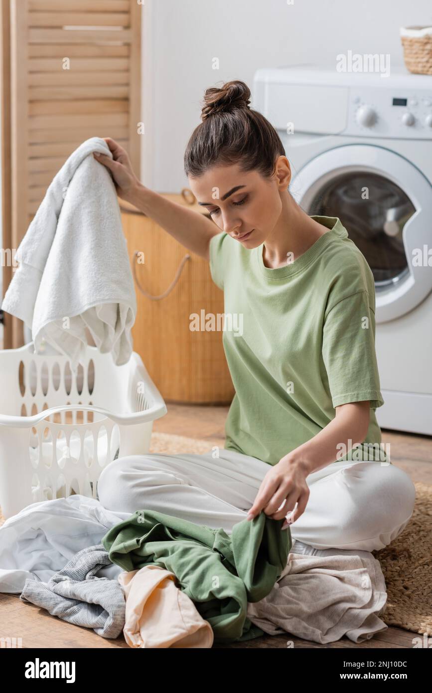 Young woman sorting clothes on floor in laundry room,stock image Stock ...