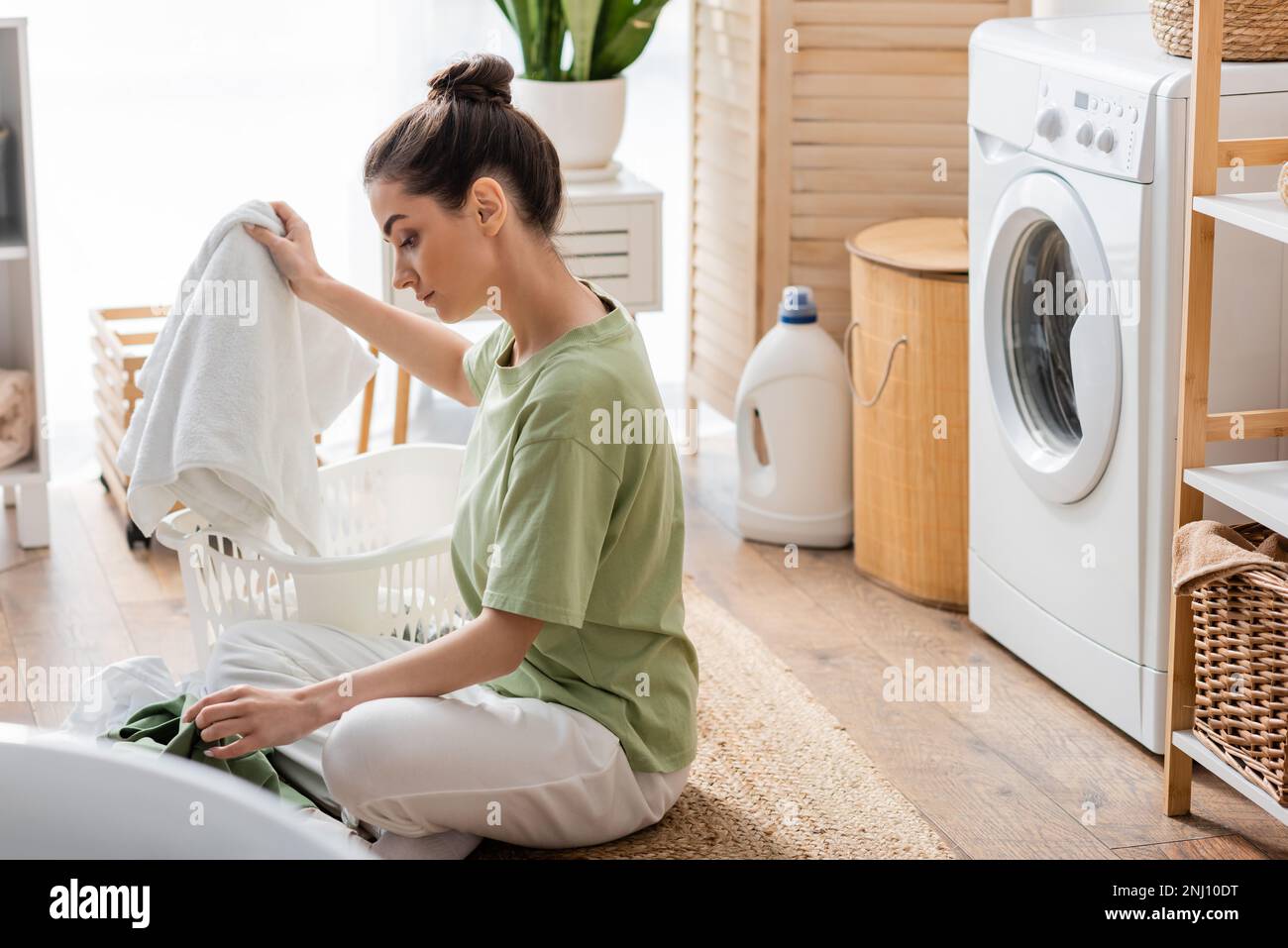 Side view of brunette woman sorting clothes in laundry room,stock image ...