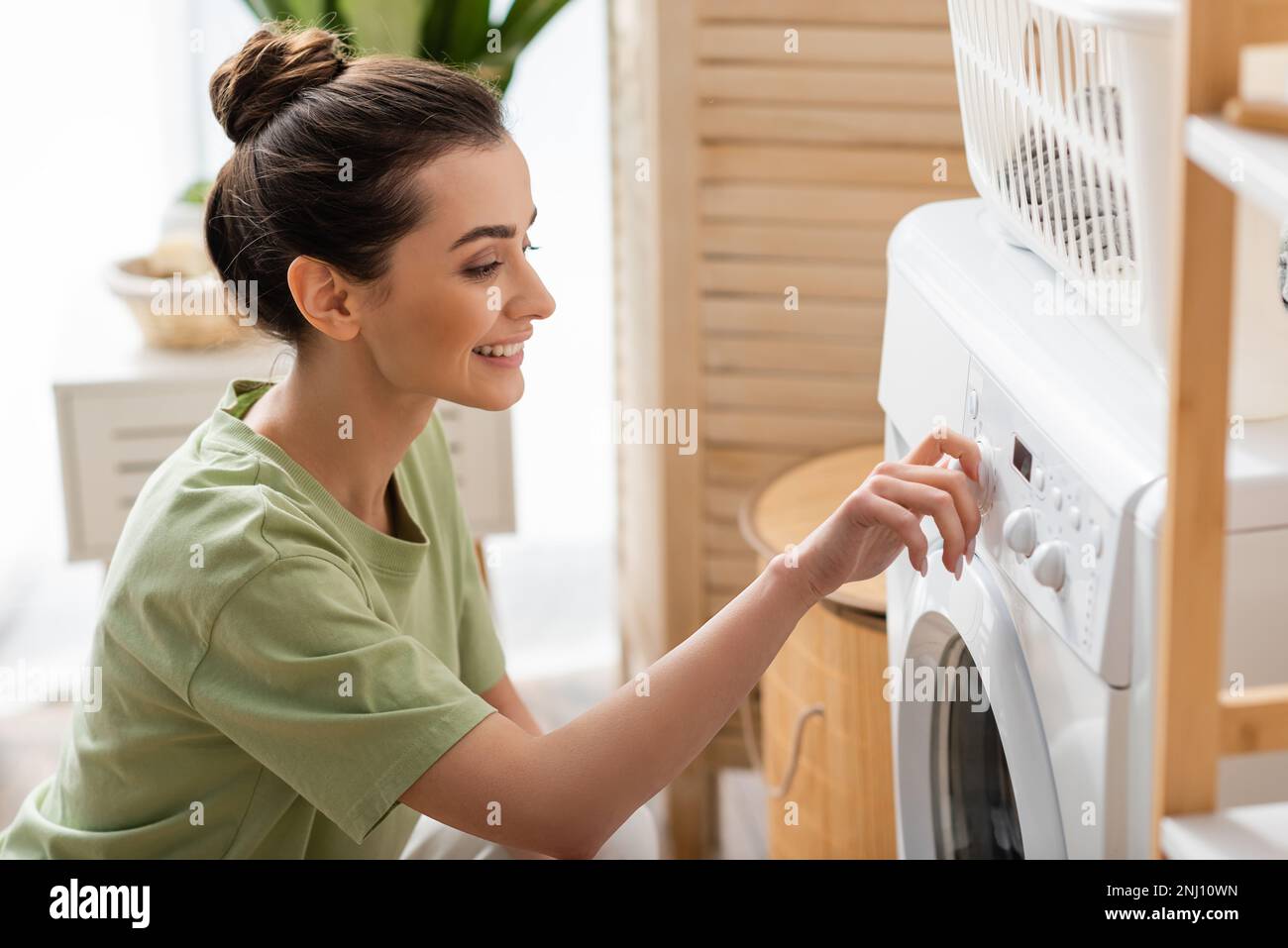 Positive young woman switching washing machine at home,stock image ...