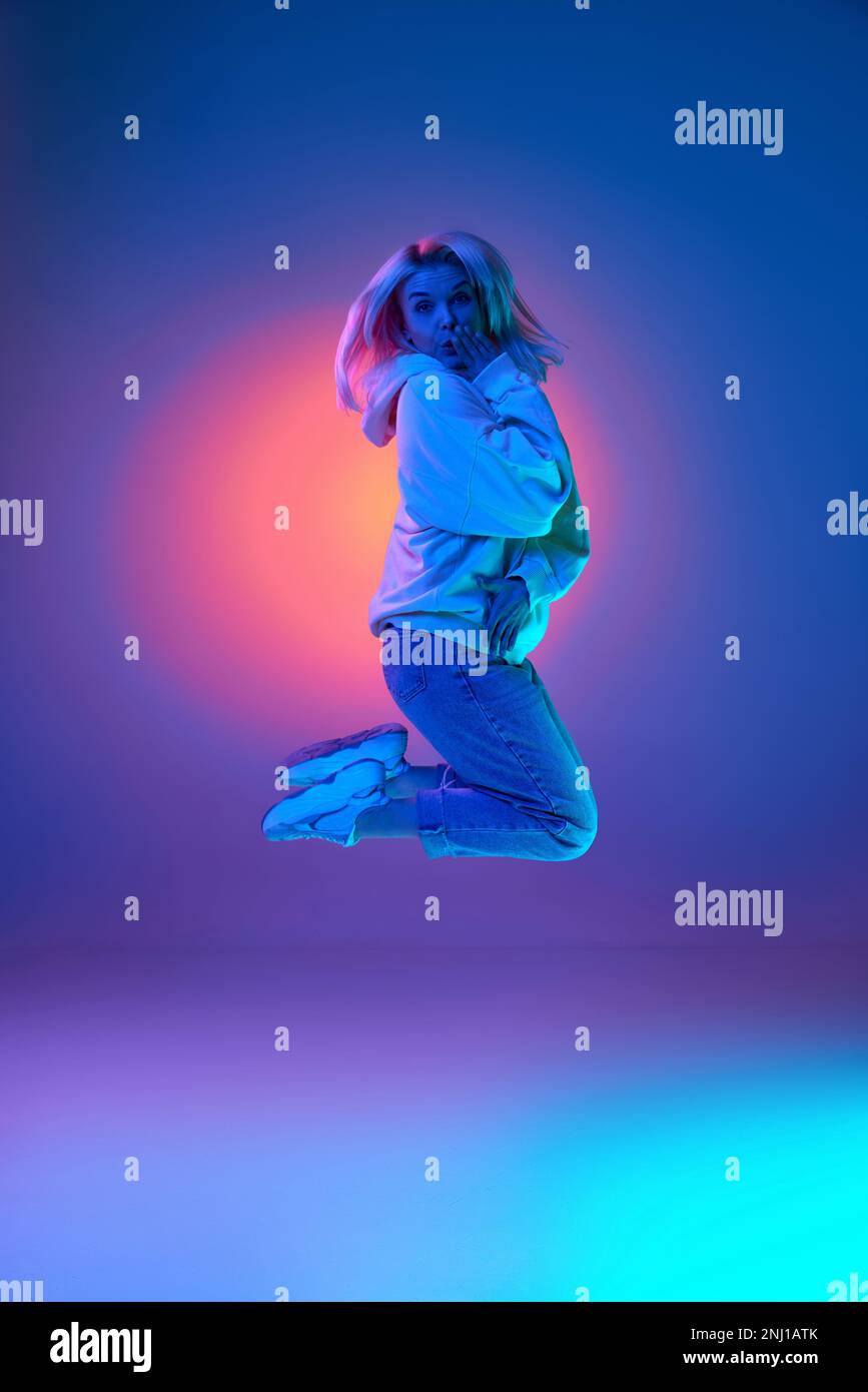 Surprise. Emotive young woman in casual clothes jumping over gradient ...