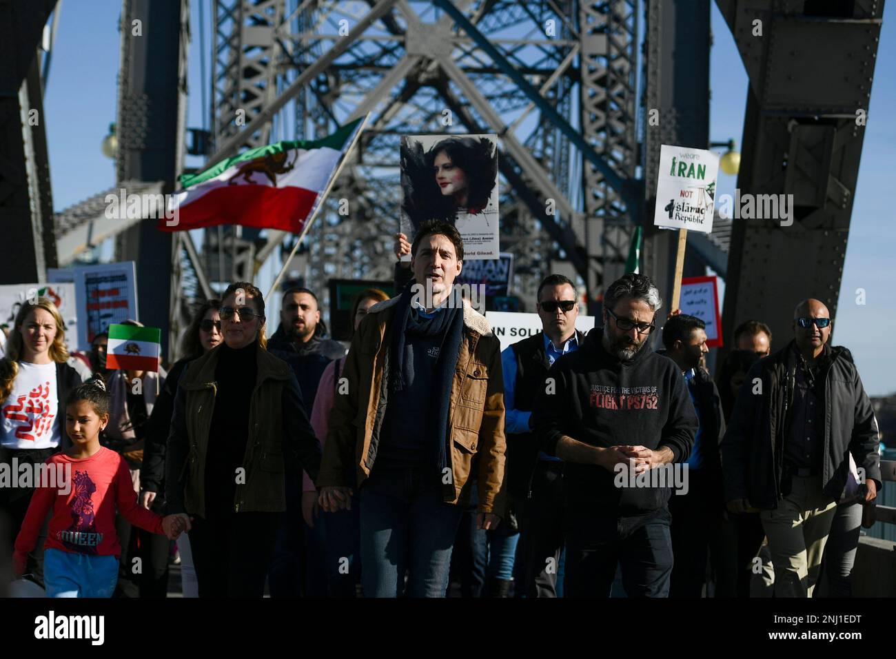 A poster with the image of Masha Amini is held up behind Canadian Prime ...