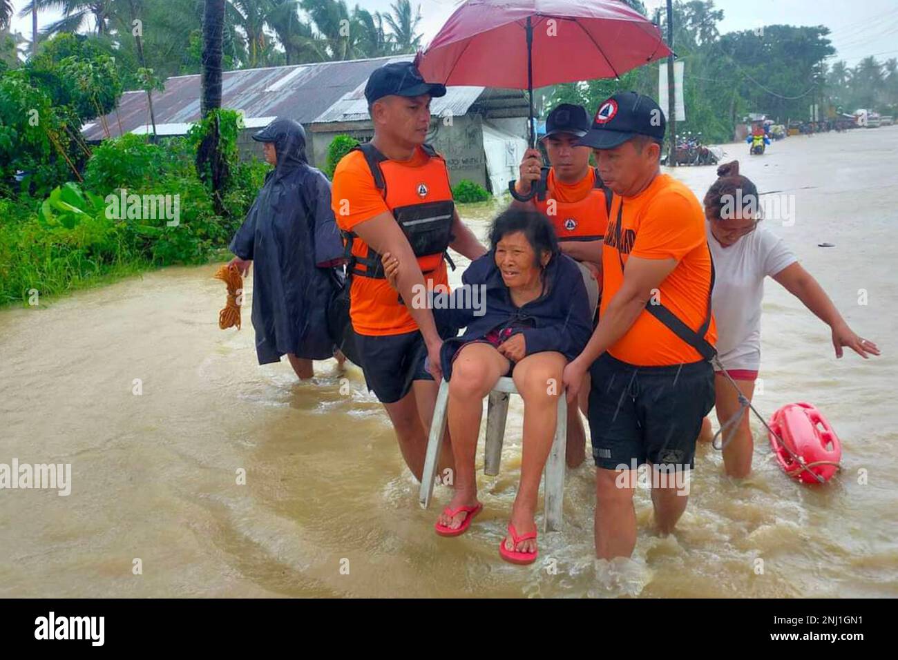 In this photo provided by the Philippine Coast Guard, rescuers evacuate residents from flood ...